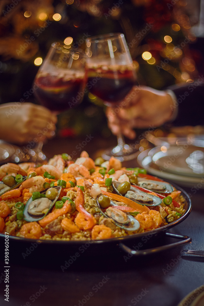 People sharing Spanish dinner table with assortment of dishes. paella ...