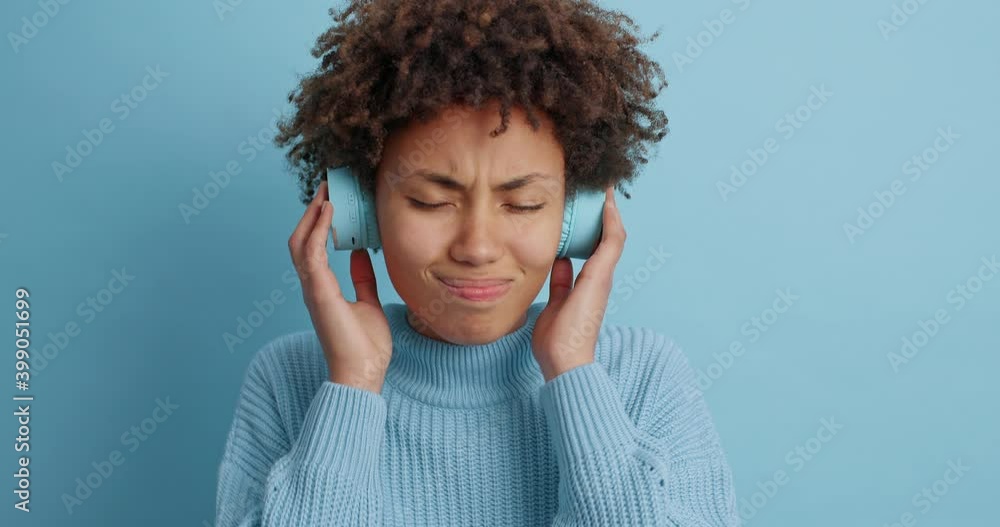 Relaxed dark skinned girl catches every bit of music wears stereo ...