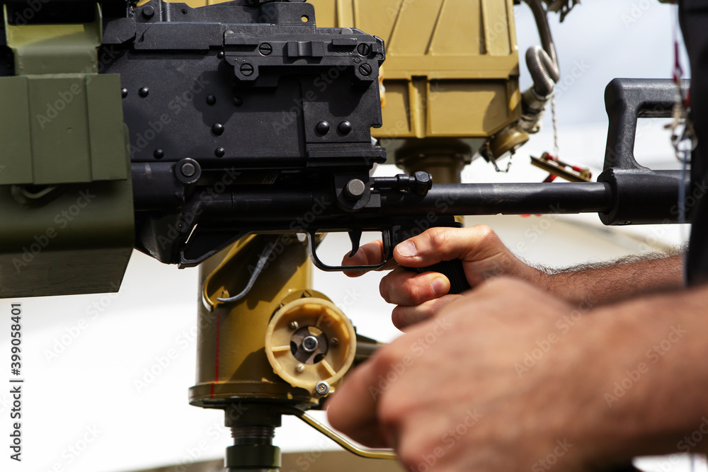 Hand on the trigger of a heavy machine gun. Military actions of warring ...