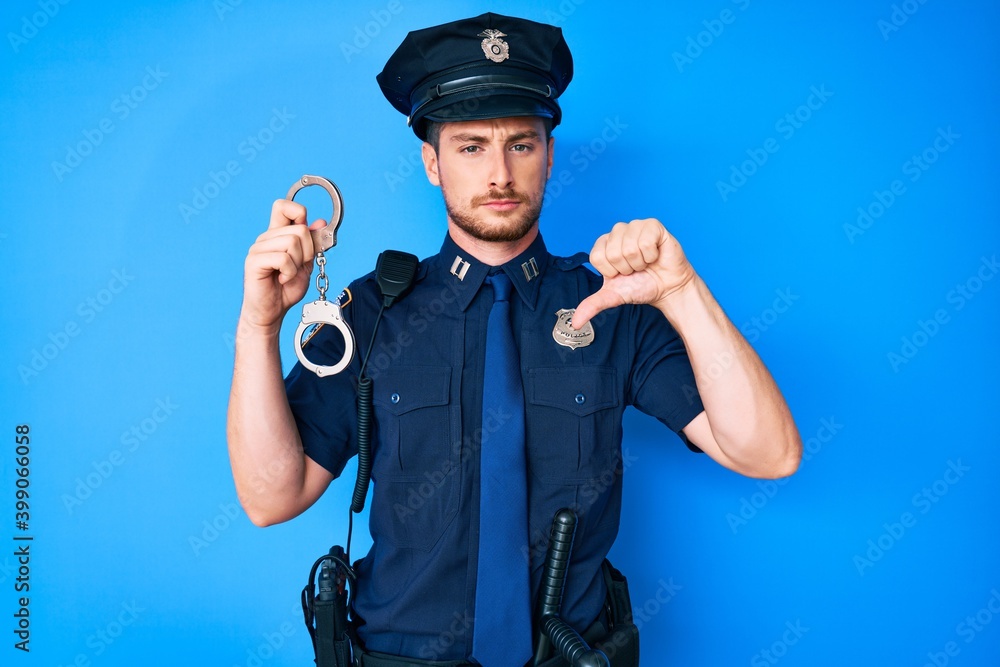 Young caucasian man wearing police uniform holding handcuffs with angry ...