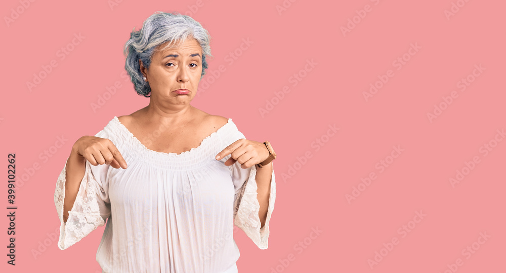 Senior woman with gray hair wearing bohemian style pointing down ...