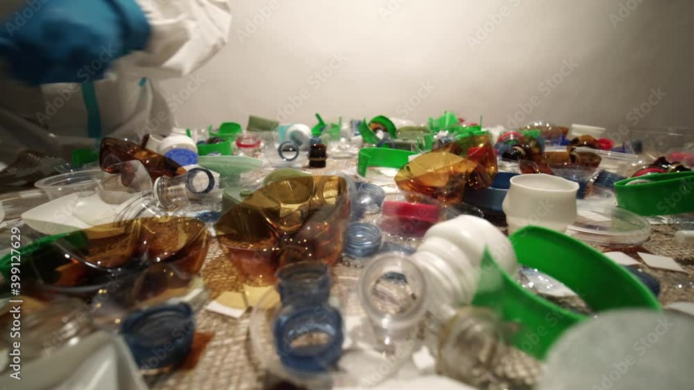 Recycle worker with blue gloves, sorting one time used plastic bottles ...