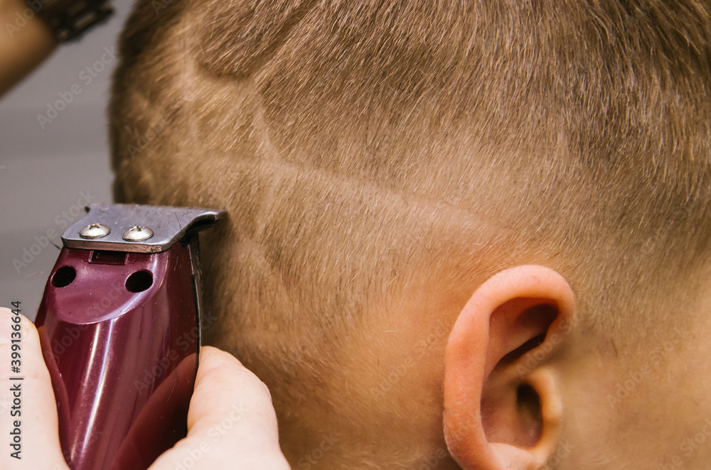 The spider-Man symbol is shaved by a clipper on a child's head. Stock Photo | Adobe Stock