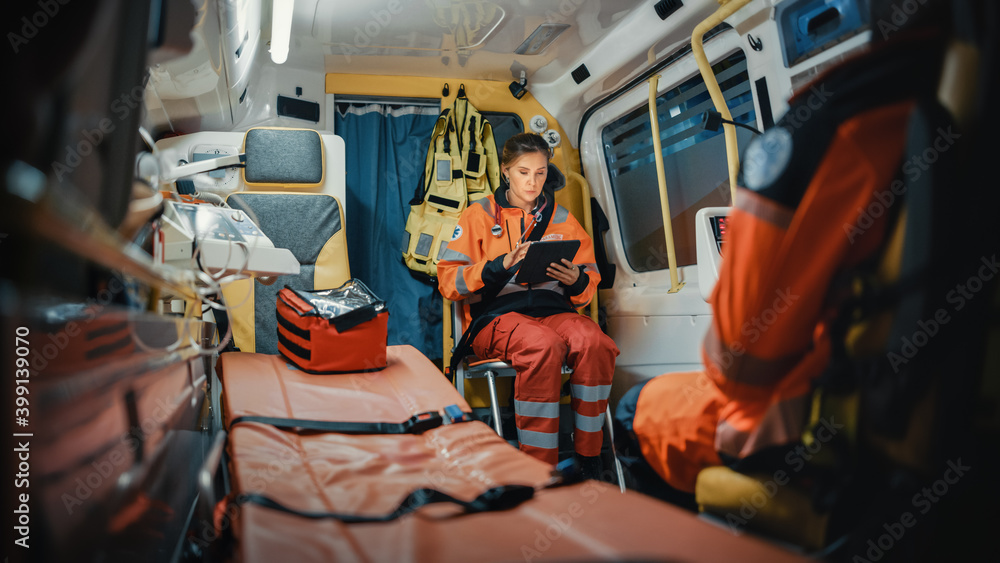 Professional Female EMS Paramedic Using Tablet Computer while Riding in ...