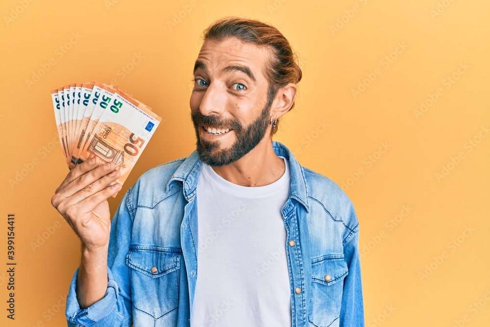 Attractive man with long hair and beard holding bunch of 50 euro ...