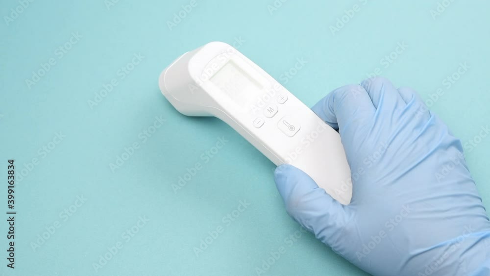 hand in blue latex gloves hold an electronic thermometer to measure ...
