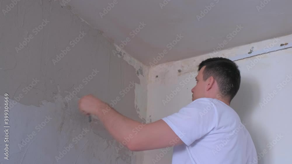 Plasterer man spackling wall with putty plaster aligning wall with ...