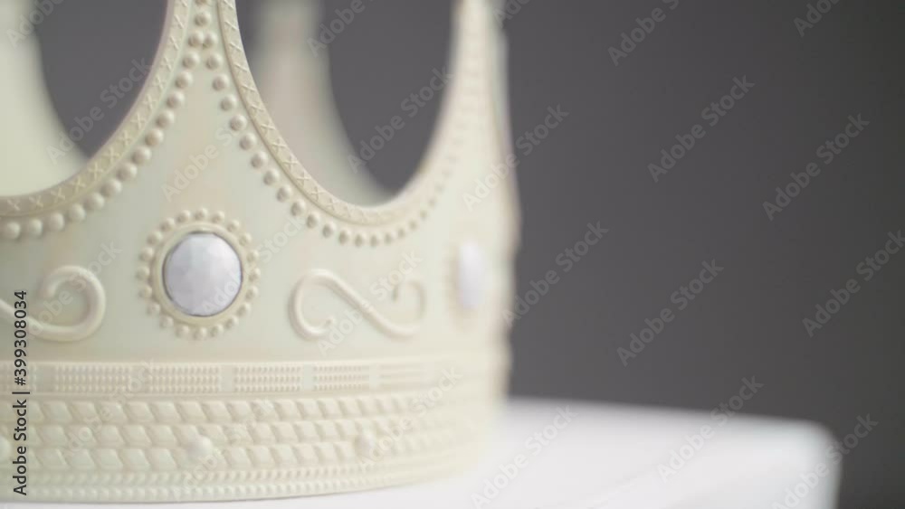 Close up of a beige crown on a pedestal with ornaments and white pearl ...