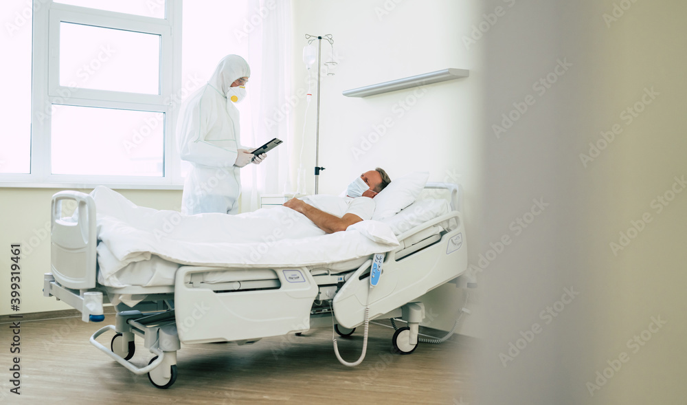 An adult male patient lies on a bed in a hospital ward while he is ...