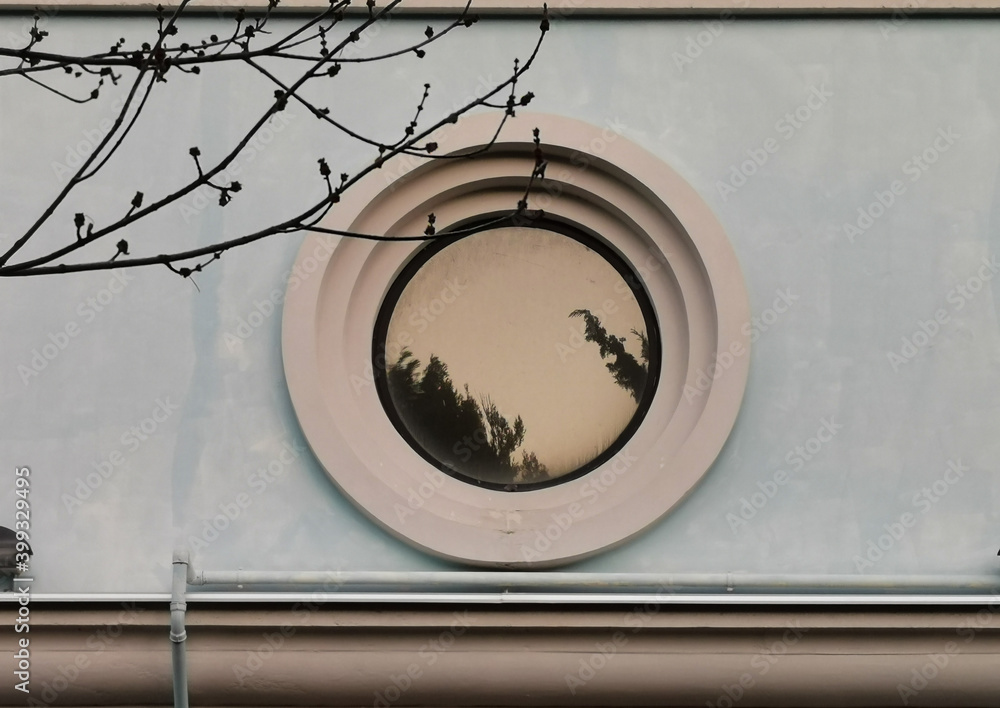 Finestra rotonda - rosone su parete azzurra con alberi riflessi nel ...
