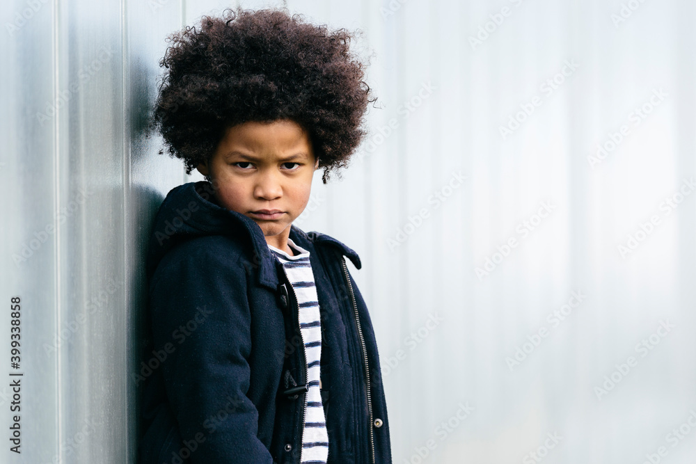 Black child with afro hair, looking at the camera, with anger ...