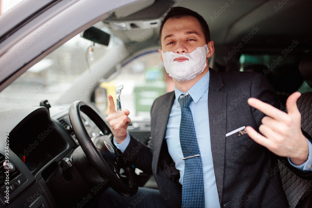 Businessman shaving in car by razor and foam at the wheel. Shaving man ...