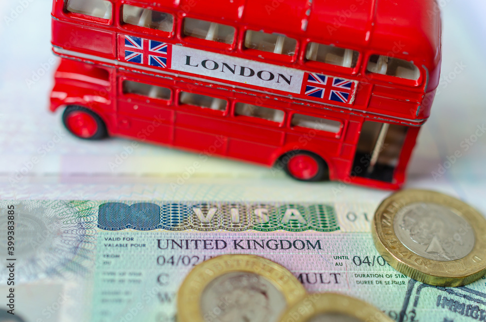 UK visa sticker in a passport surrounded by pound coins and double ...