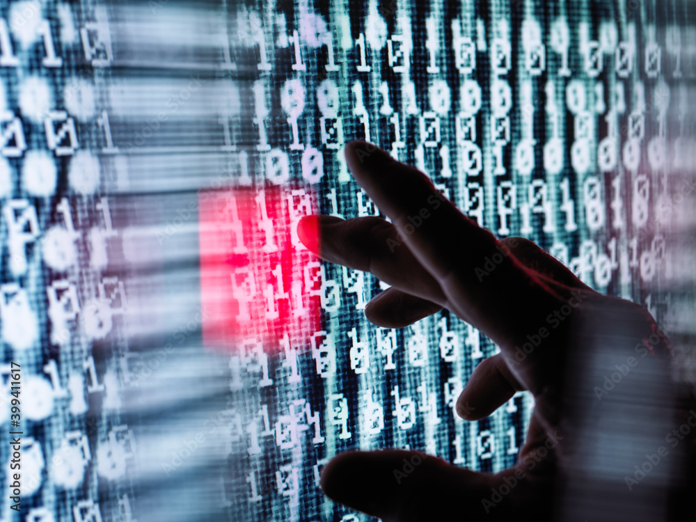 Cropped image of human finger touching computer screen with binary code ...