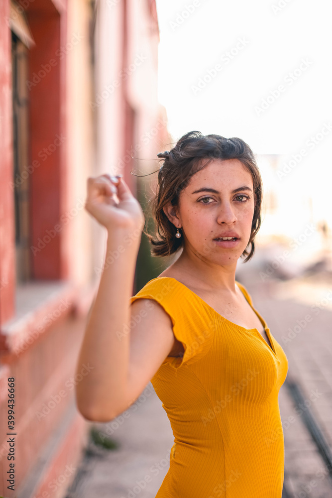 Cheerful young woman wearing sneakers and yellow skirt, modeling ...