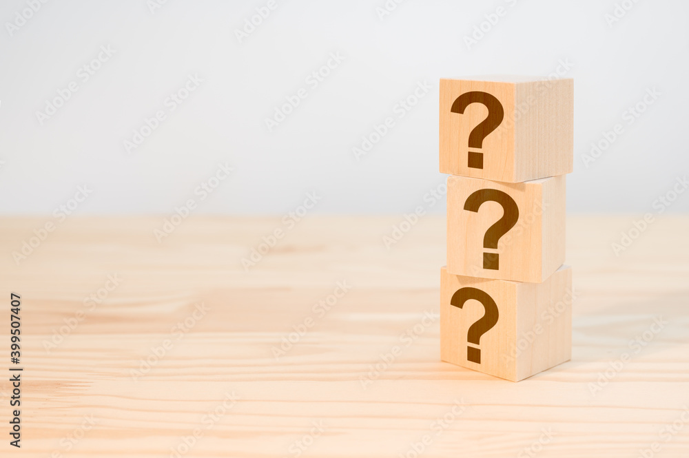 Wooden cube block shape with sign question mark symbol on wood table. column of wooden blocks ...
