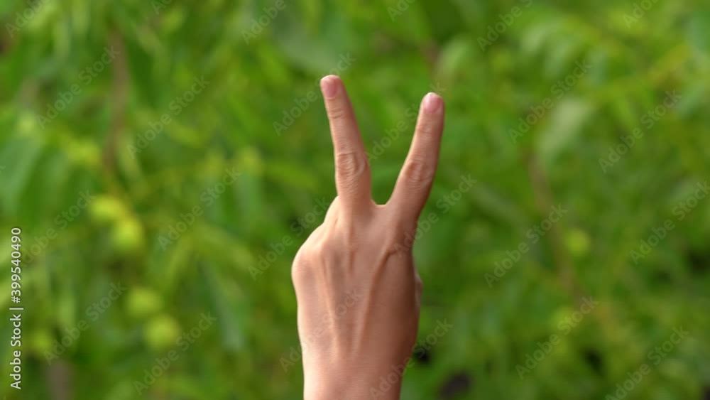Woman raising two fingers up and showing peace or victory symbol or ...
