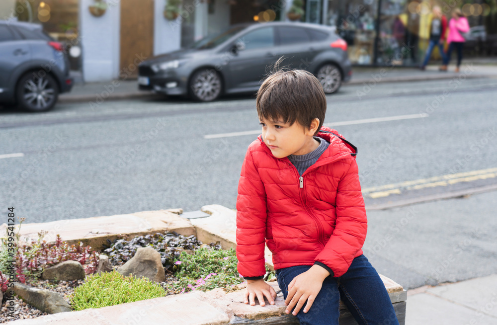 Lost Kid sitting alone next to a busy street in a center of city, Young ...