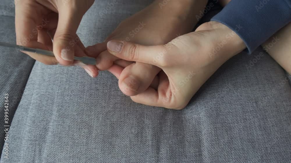 Woman is making pedicure herself removing cuticle and pterygium on toe ...