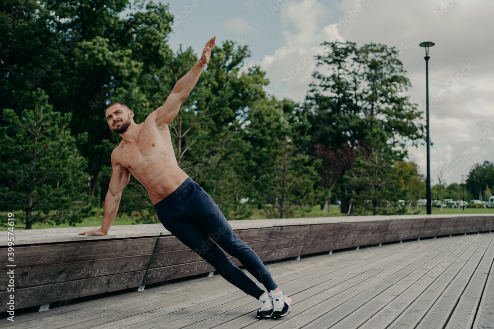 Active sportsman trains for strong healthy muscular body, poses outdoor ...