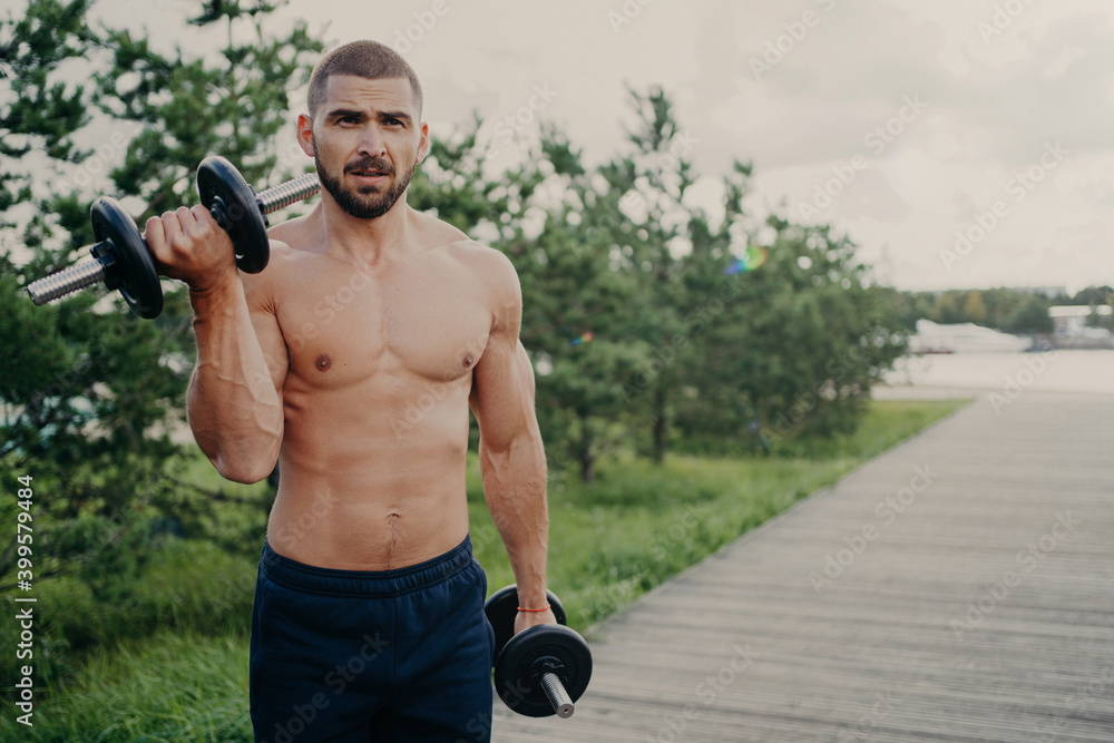 Strong muscular bodybuilder prepares for athletic competition, raises ...