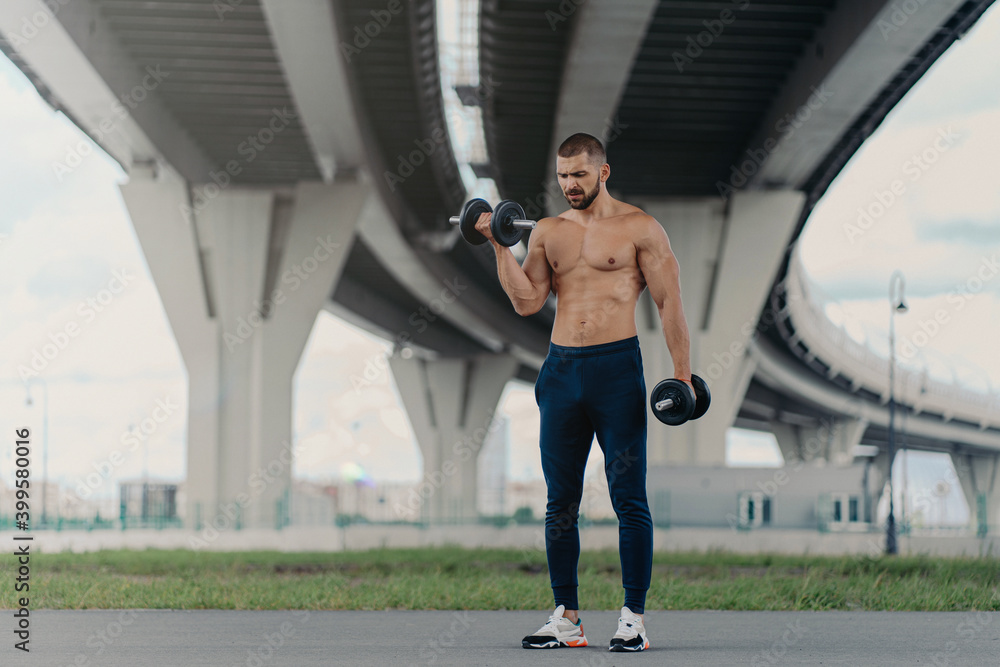 Healthy strong bodybuilder lifts heavy barbells, has workout outdoor ...