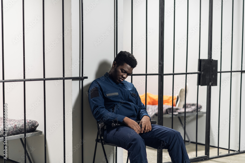A prison warden guards cells with prisoners sentenced to life in orange ...