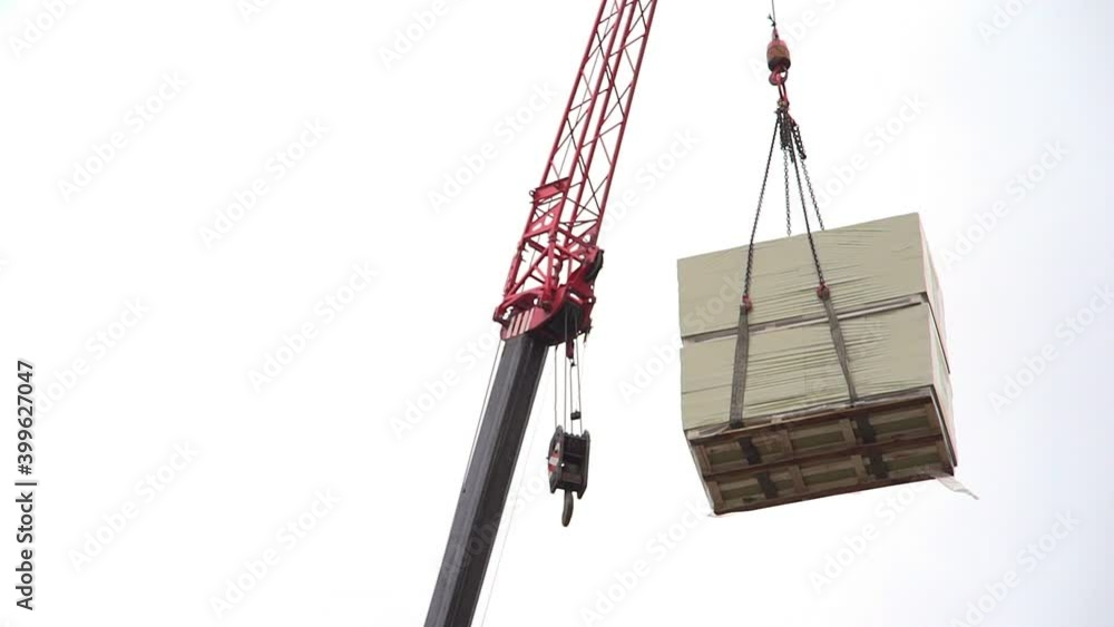 loads with building materials on a pallet are tied to a hook on a rope ...