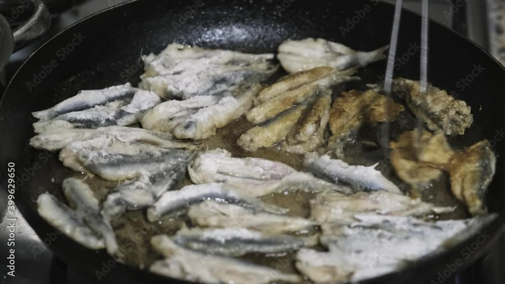 Fried anchovies in a pan. Cooking anchovies. Small fish fry in the pan ...