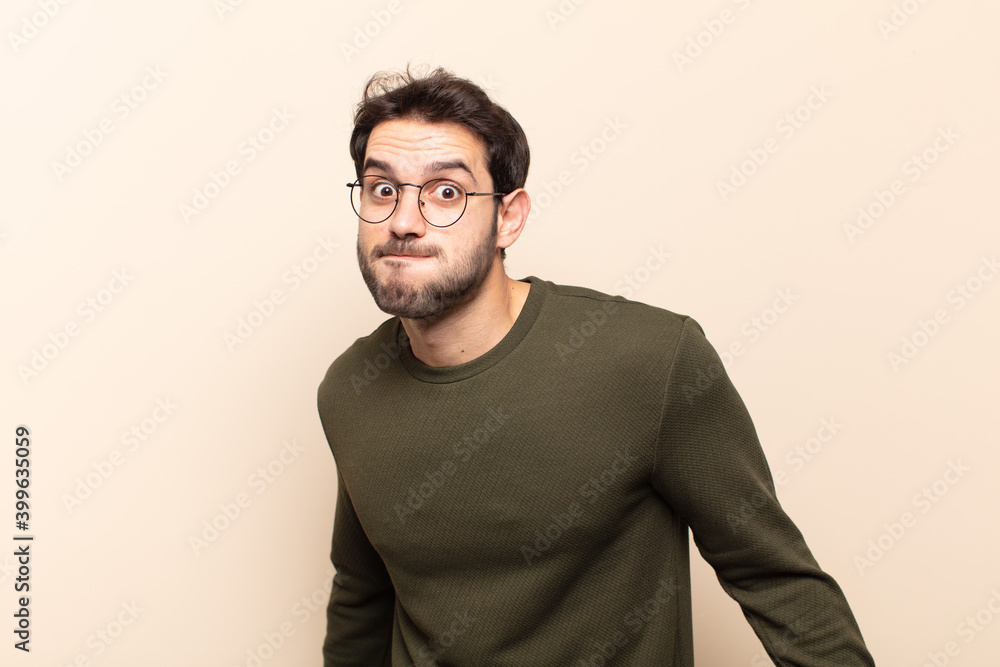 young handsome man with a goofy, crazy, surprised expression, puffing ...