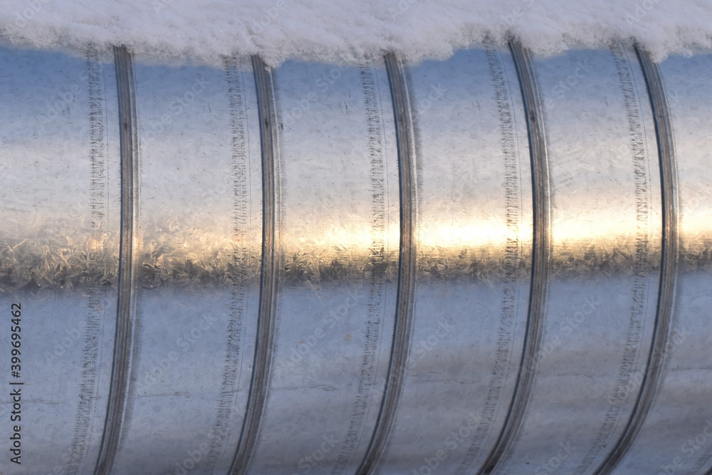 Horizontal aluminum pipe or conduit, above ground, with snow on top ...