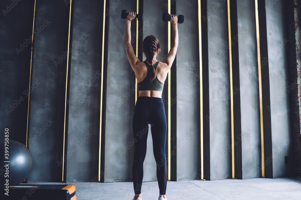 Back view of female in trendy activewear with muscular figure lifting ...
