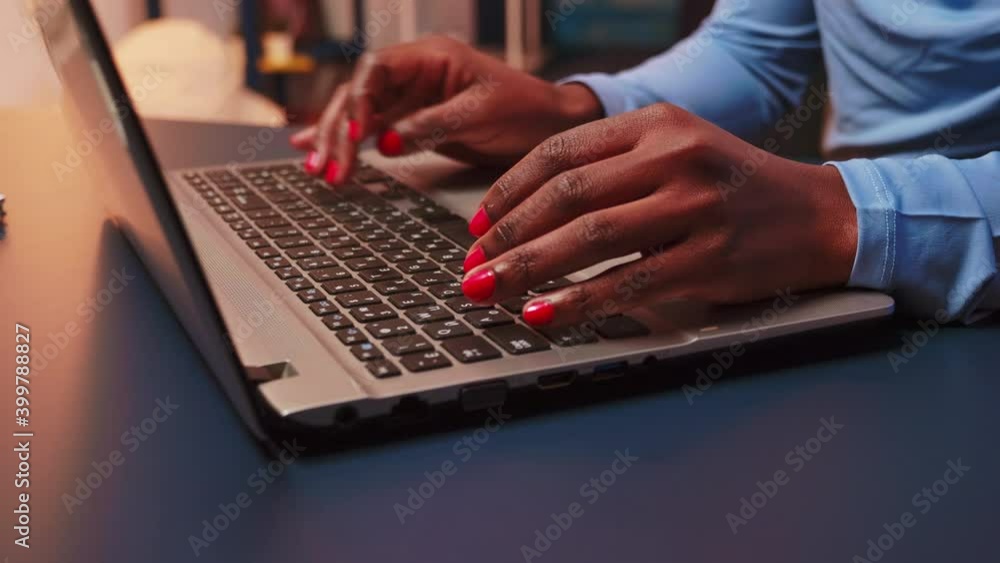 Close up of black woman typing on keyboard of laptop sitting at desk in ...