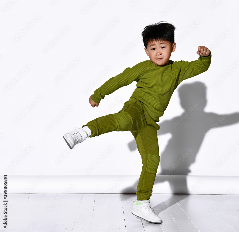 Fashion portrait of a cute little kid boy in stylish green sports suit ...
