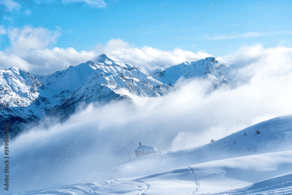 Snow covered mountain peaks above the clouds. High mountains in winter ...