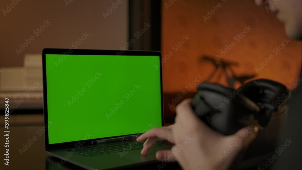 Man with virtual reality helmet typing on a laptop keyboard with green ...