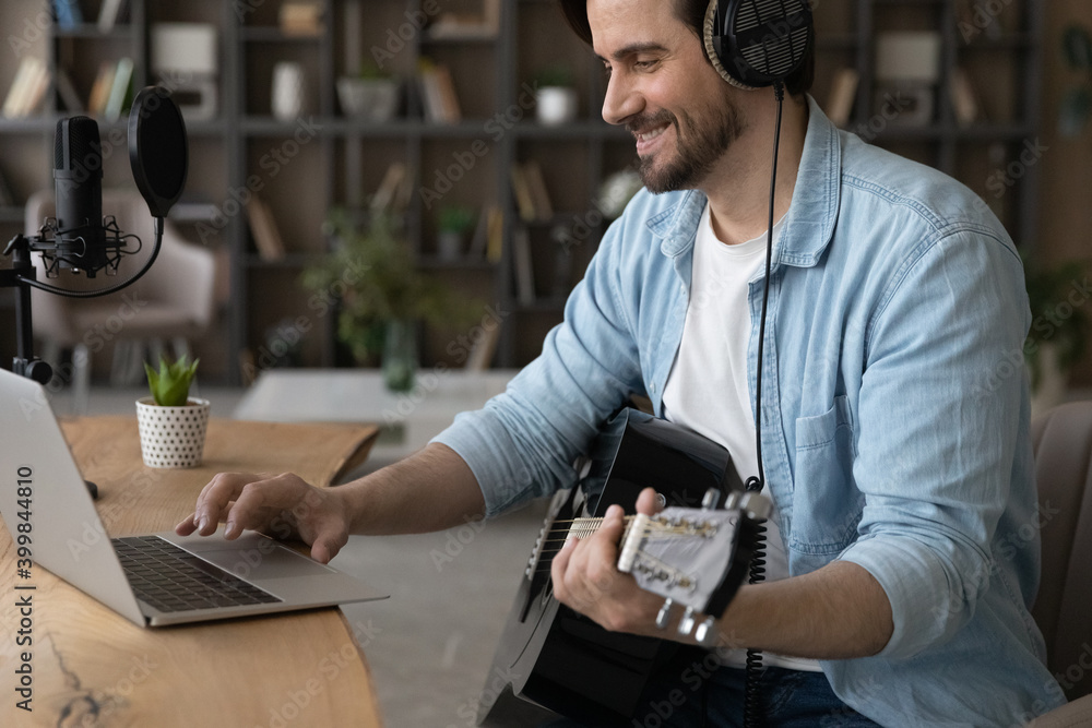 Foto de Happy millennial man musician hold play guitar watching online ...