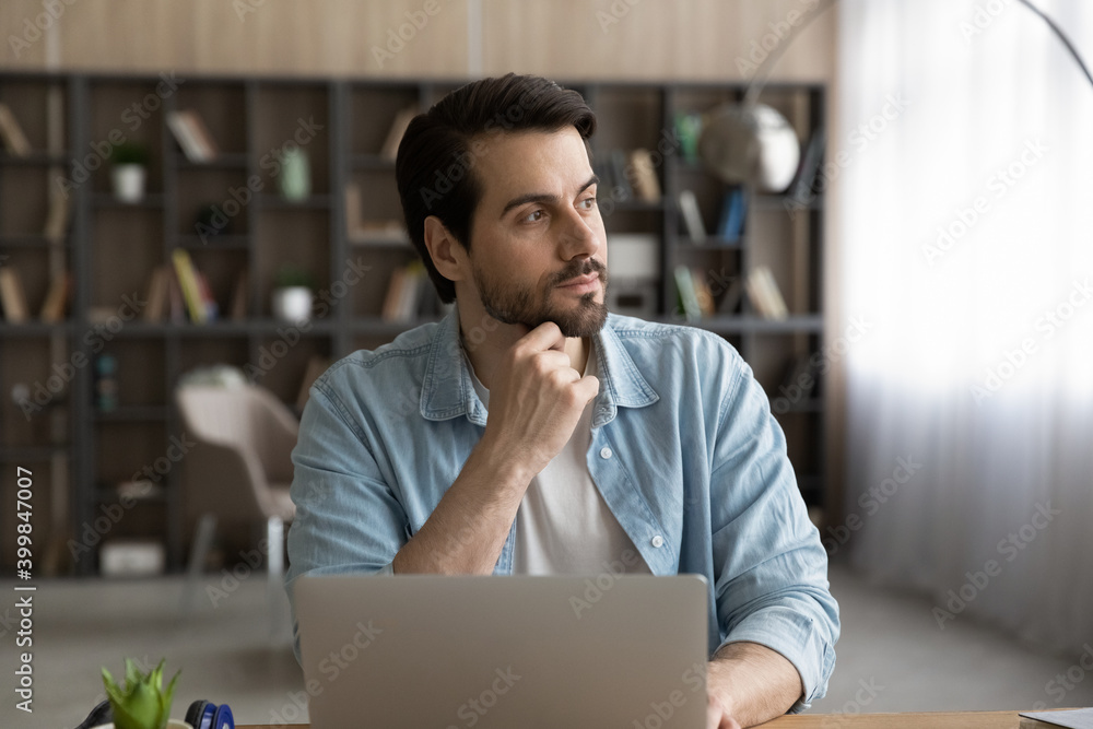 Pensive young Caucasian woman work on laptop in home office look in ...