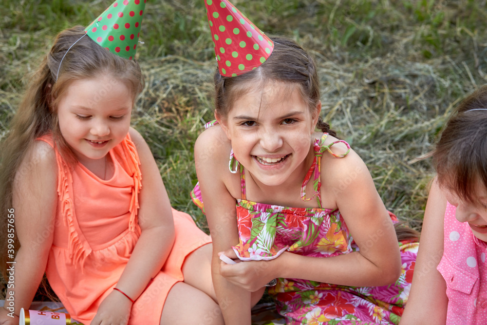 Cute girls in a festive hat and bright dresses celebrate their birthday ...