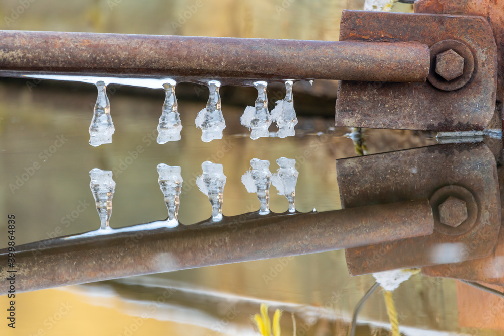 Icicles frozen ice hanging off rusting pole above water with stunning ...