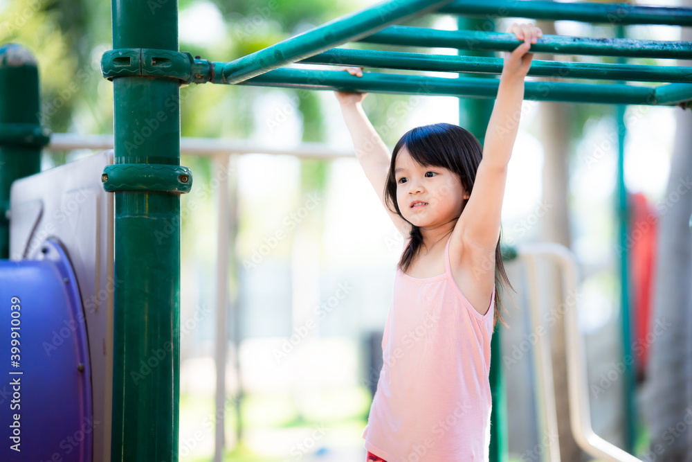 Young Asian girl hanging on monkey green bars in playground. Summer ...