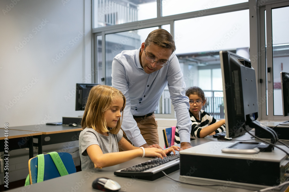 Focused pretty blonde girl typing on keyboard in classroom. Serious ...