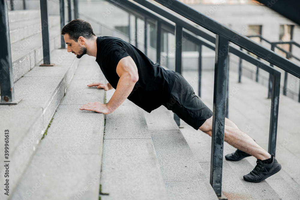 Well built young man pushing up from stairs. Side view. Athletic man ...