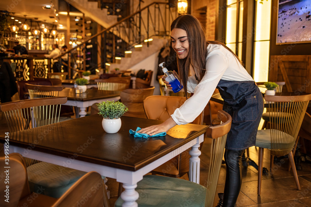 Waitress cleaning a table at a restaurant. Happy waitress cleaning a ...