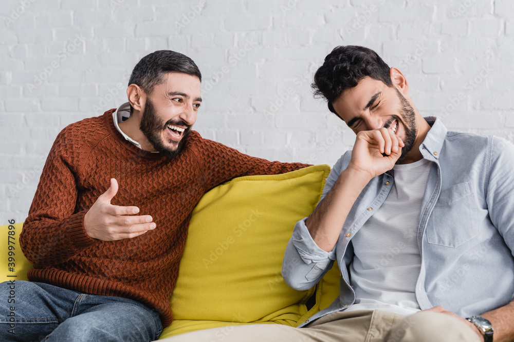 Foto de Mature hispanic man talking with laughing son on couch, two ...