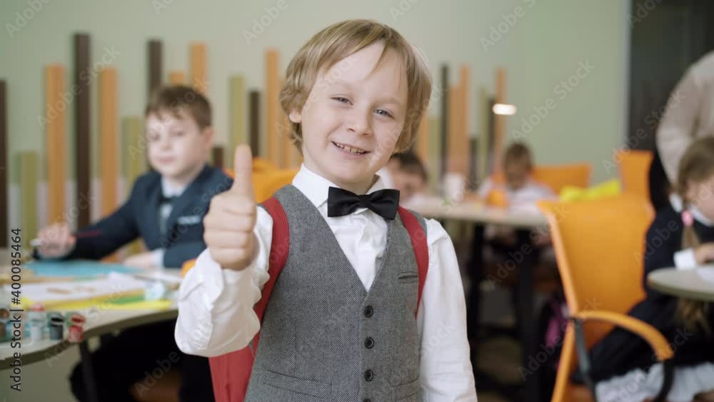 Portrait of cute happy schoolboy showing thumb up and smiling at camera ...
