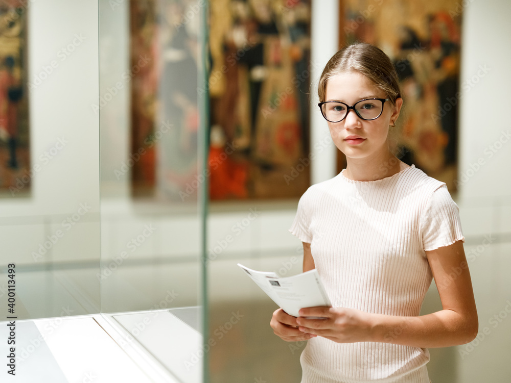 Positive tween girl observing with interest exhibition in art gallery ...