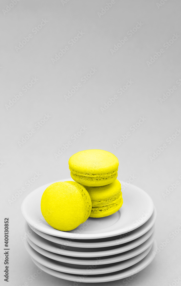 Yellow macaroons with plates on a gray background. Fashionable color ...