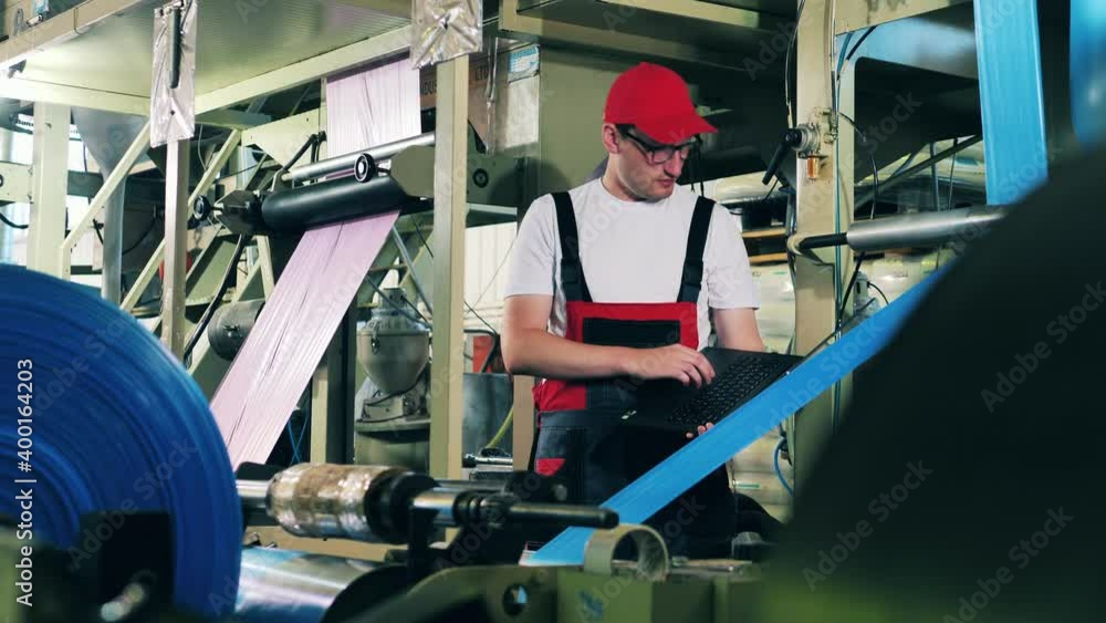 Male factory worker monitoring plastic bag production process with his ...