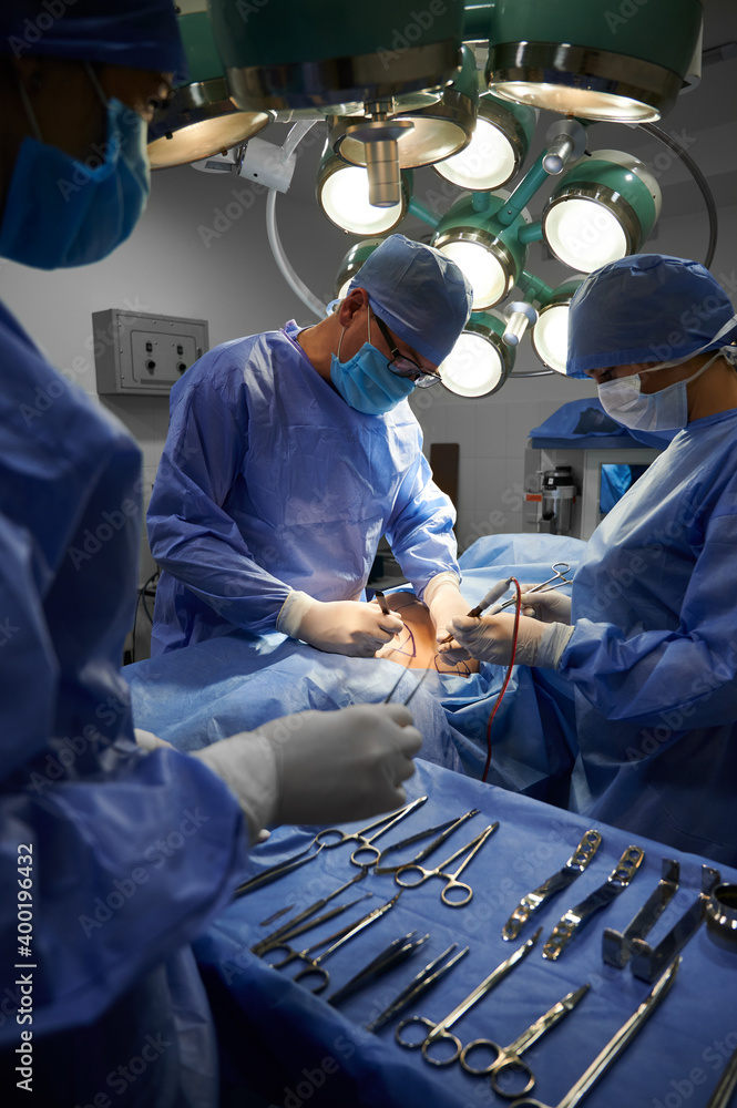 Surgical team doing aesthetic surgery in operating room. Doctors doing ...